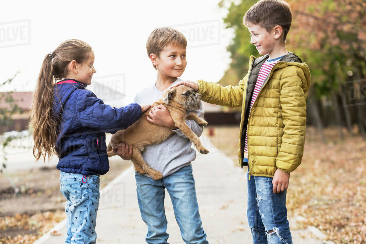 Children playing with dog outdoors - Royalty-free Stock Photo | Dissolve