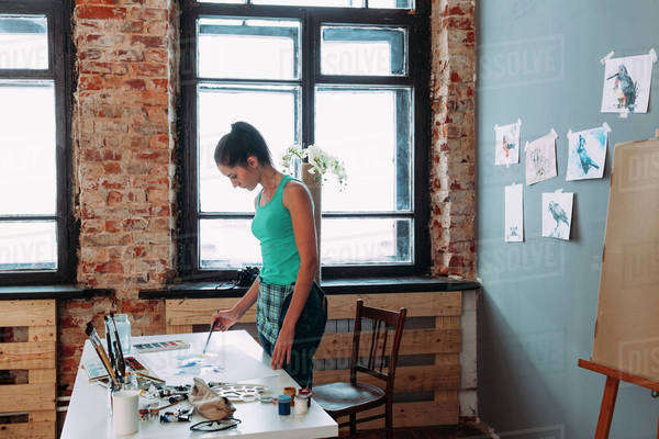 Side view of artist painting at table in art studio - Royalty-free ...