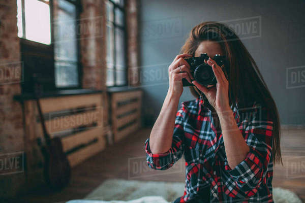 Woman photographing through SLR camera in bedroom at home - Royalty ...