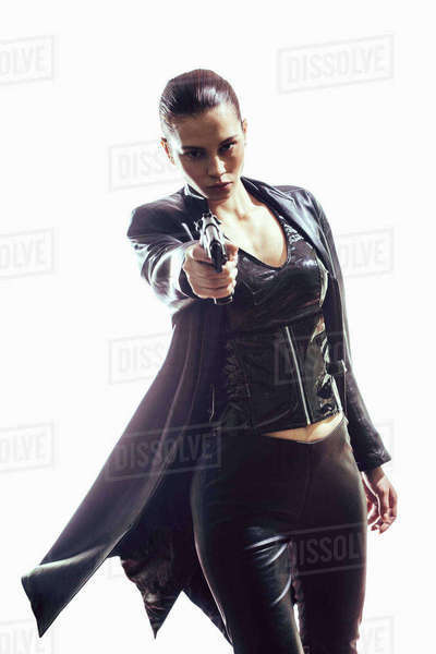 Portrait of female spy aiming gun while standing against white ...