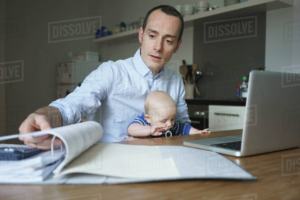 Serious father carrying son and reading documents at home - Royalty ...