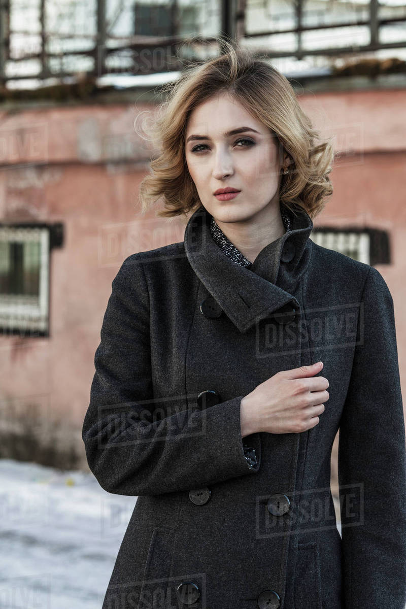 Portrait of confident young woman wearing long coat outdoors - Royalty ...