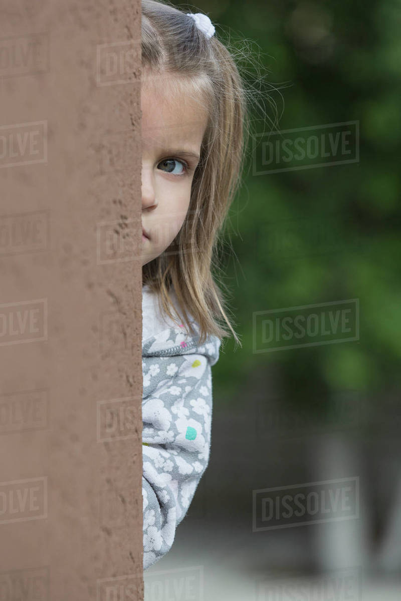 Portrait of girl standing behind wall - Stock Photo - Dissolve