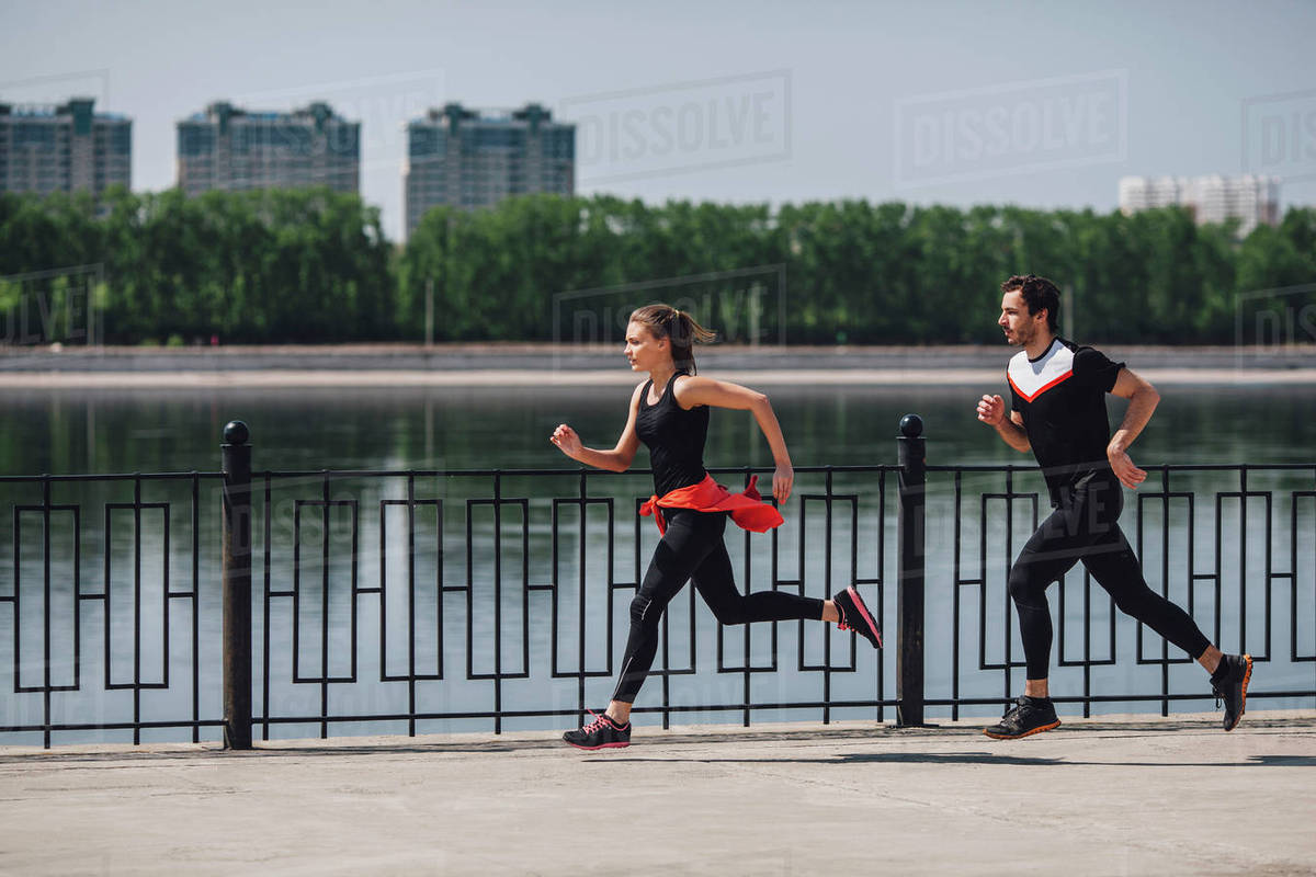 Side view of people running on promenade next to lake - Royalty-free ...