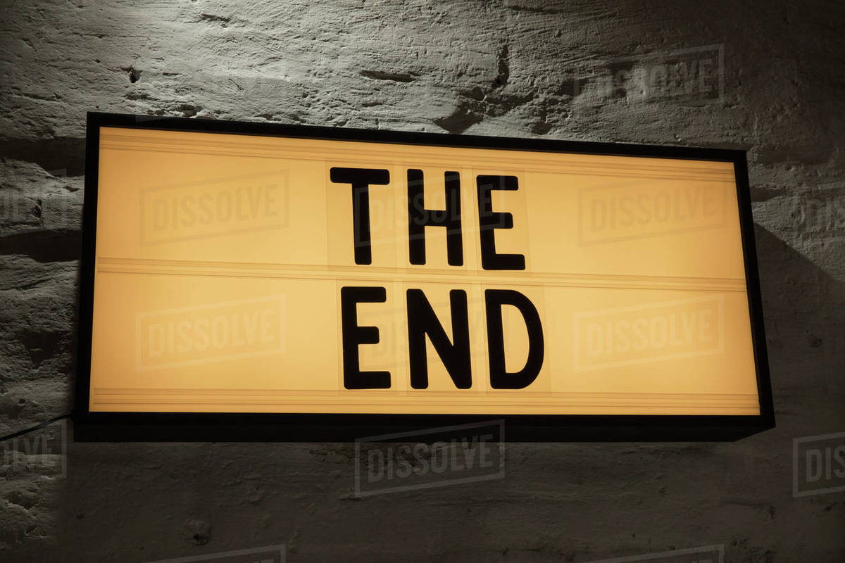 Close-up of The End signboard against gray wall - Stock Photo - Dissolve