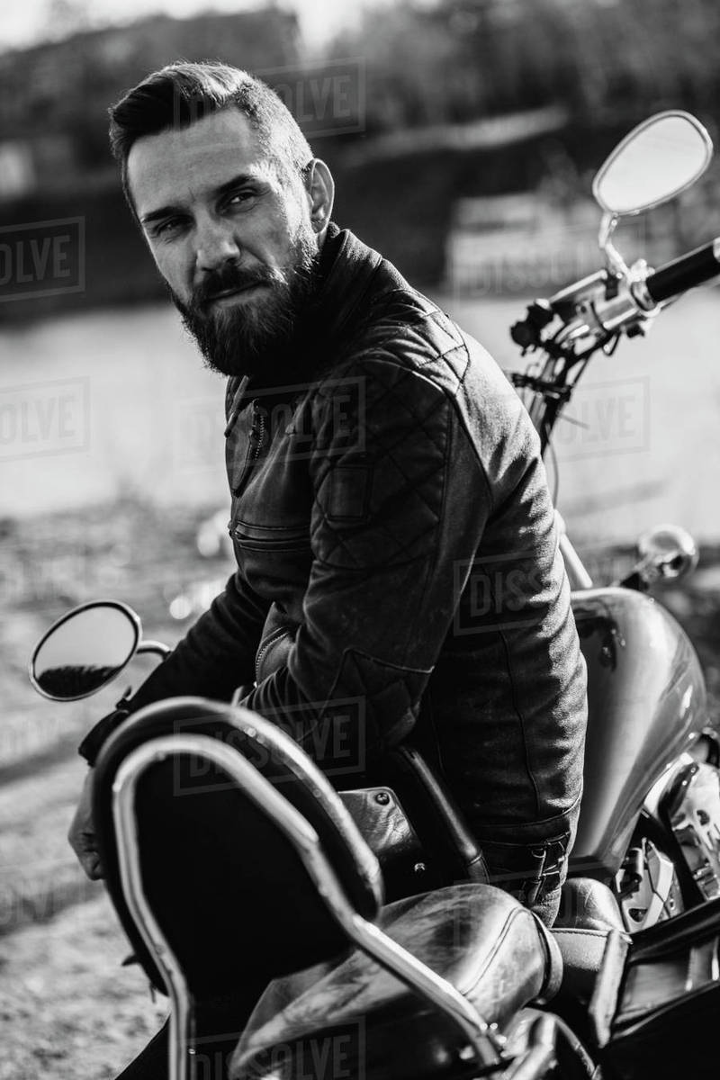 Side view of man sitting on motorcycle at lakeshore - Royalty-free ...