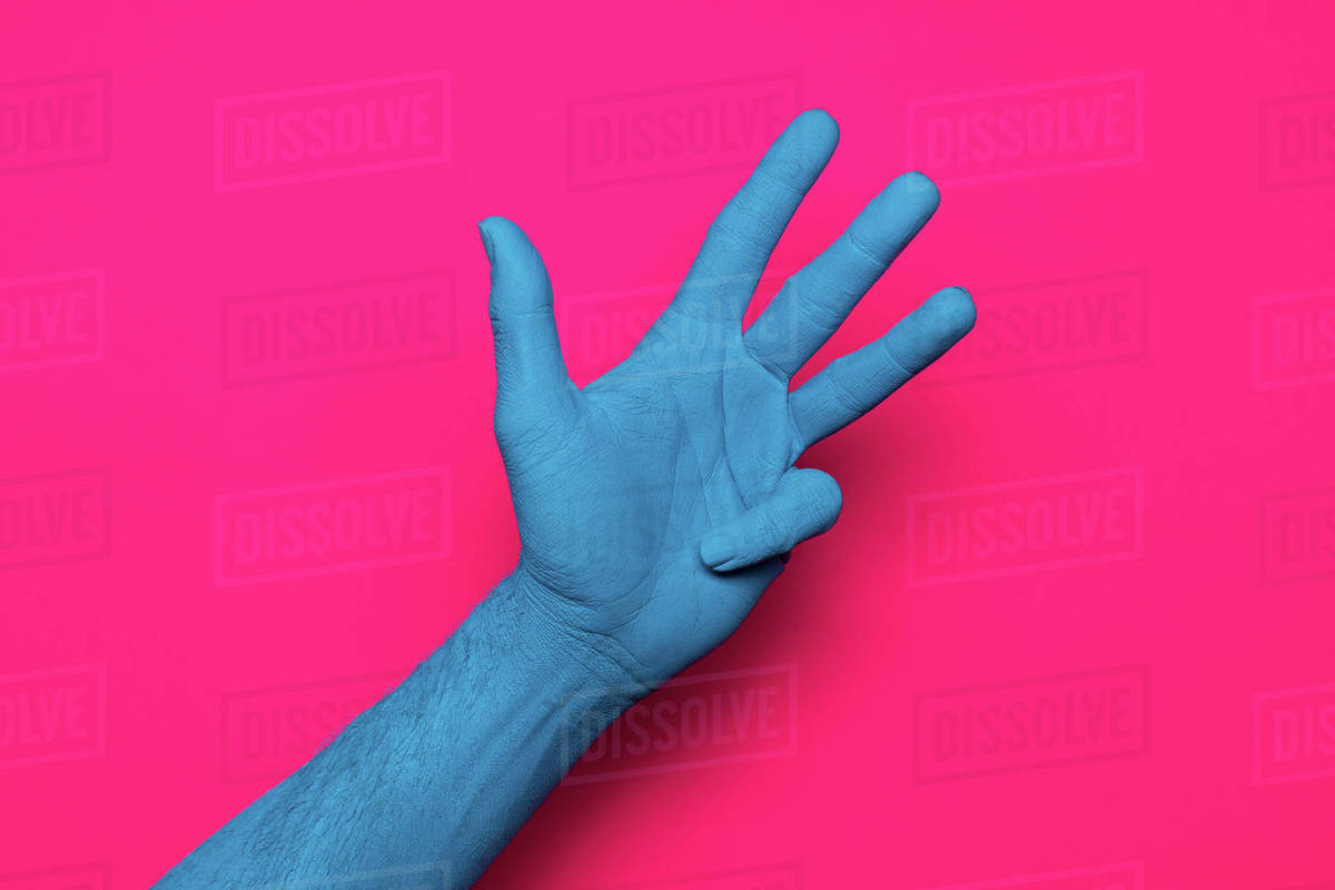 Close-up of blue painted hand gesturing against pink background - Stock ...