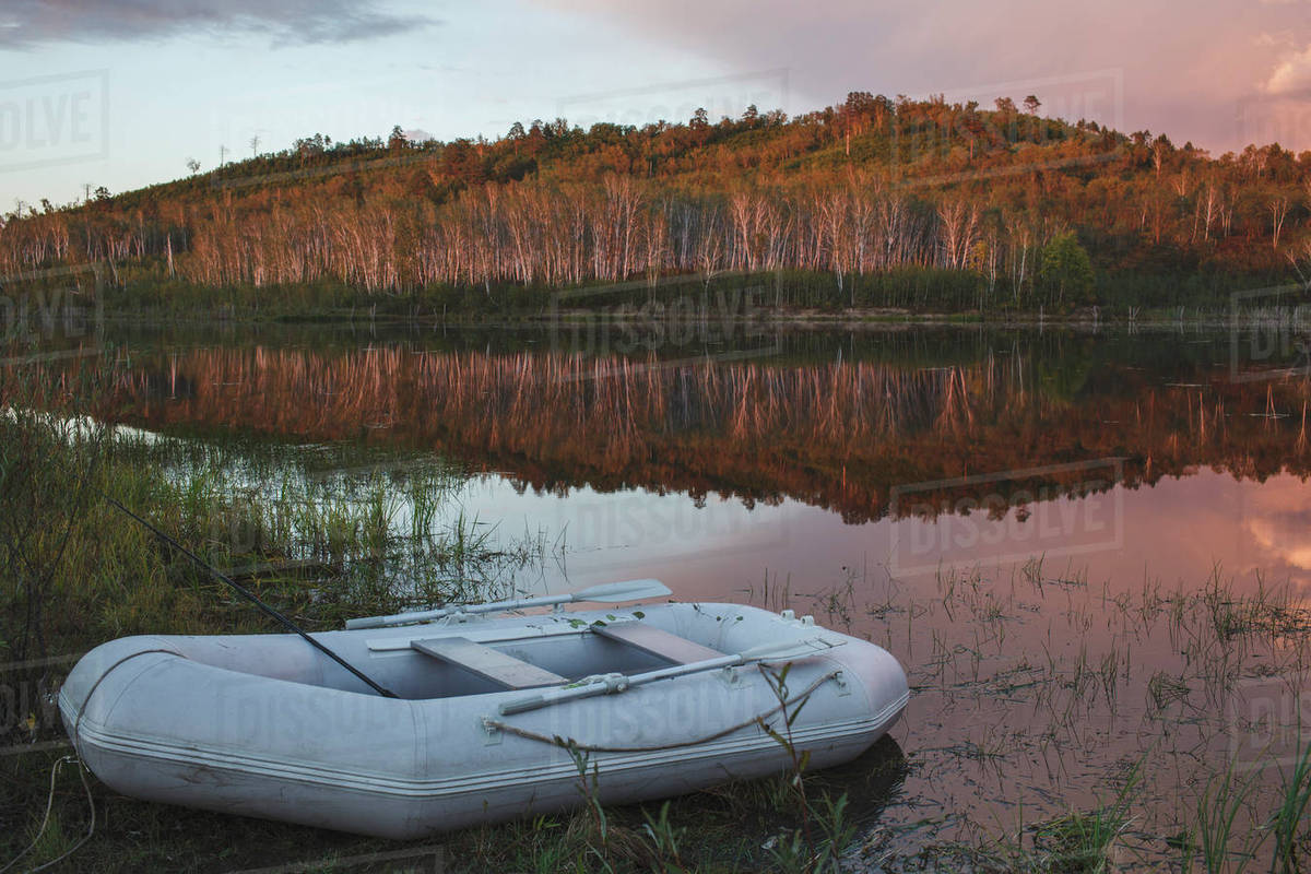 Empty inflatable raft moored on lakeshore against forest, Svobodniy ...