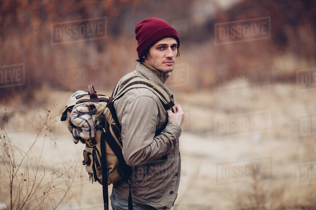 Portrait of man carrying backpack and standing in field - Royalty-free ...