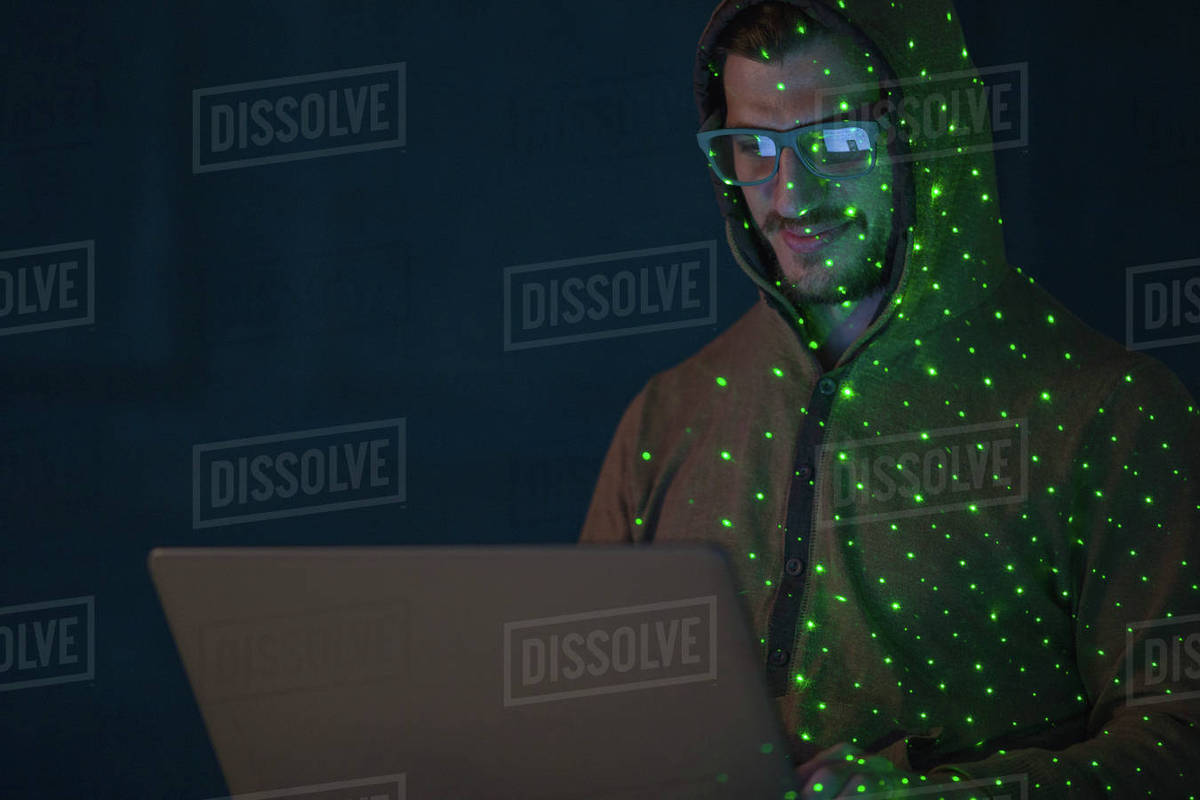 Green lights over smiling computer hacker wearing hooded shirt using ...