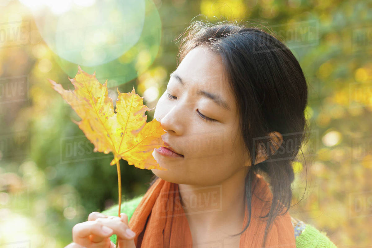 Close Up Of Young Woman With Closed Eyes Holding Dry Maple Leaf At Park