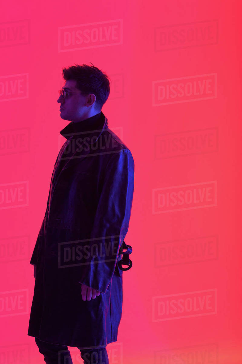 Young male fashion model standing against coral background - Stock ...