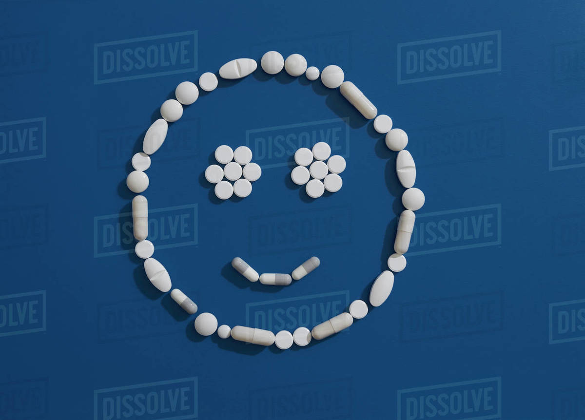Pills forming smiley face on blue background - Stock Photo - Dissolve