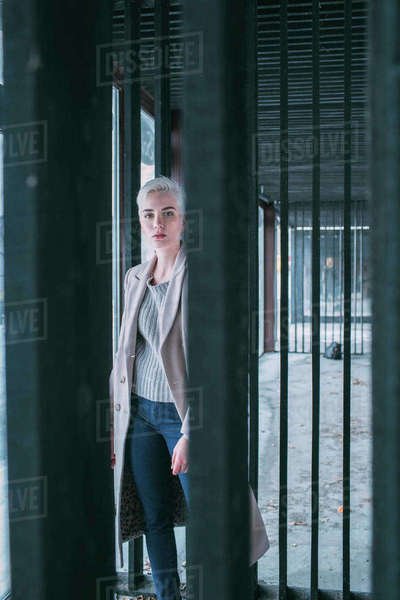 Portrait confident young woman behind gate - Stock Photo - Dissolve