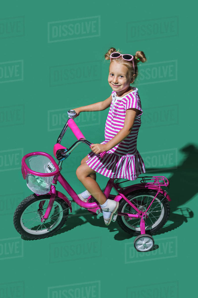 Portrait smiling girl bike riding against green background - Stock ...