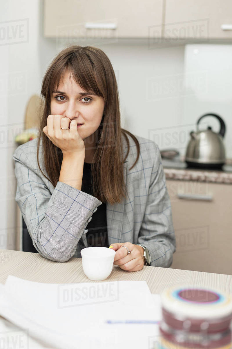 Portrait of woman sitting in kitchen - Stock Photo - Dissolve