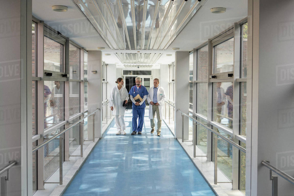 Doctors talking and walking in hospital corridor - Royalty-free Stock ...