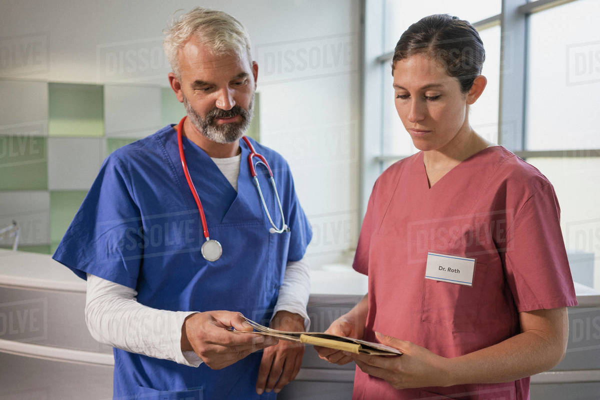 Doctors reviewing medical record in hospital - Stock Photo - Dissolve