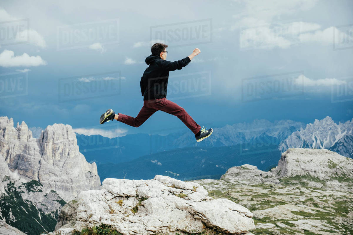 Carefree boy jumping over rocks on mountain, Drei Zinnen Nature Park ...