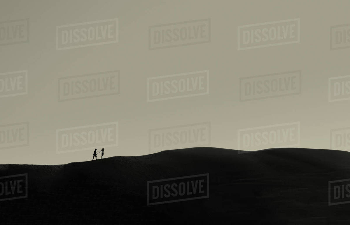 Silhouetted children walking over sand dunes, Arabian Desert, Dubai ...