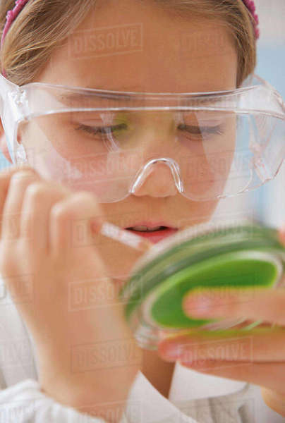 Close up junior high school girl in science goggles with petri dish ...