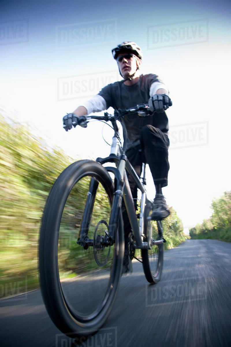Man cycling on a country road - Stock Photo - Dissolve