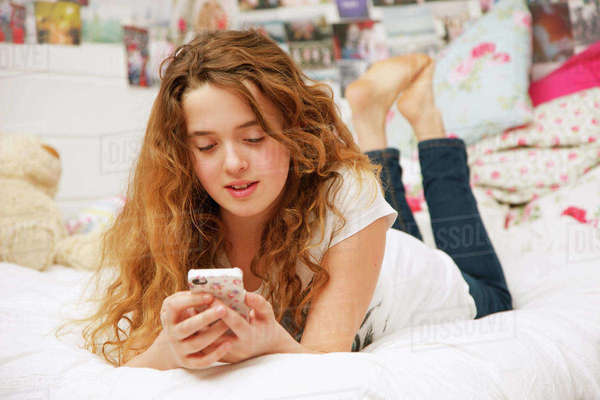 Young Girl Lying on Bed Using Cell Phone - Royalty-free Stock Photo ...