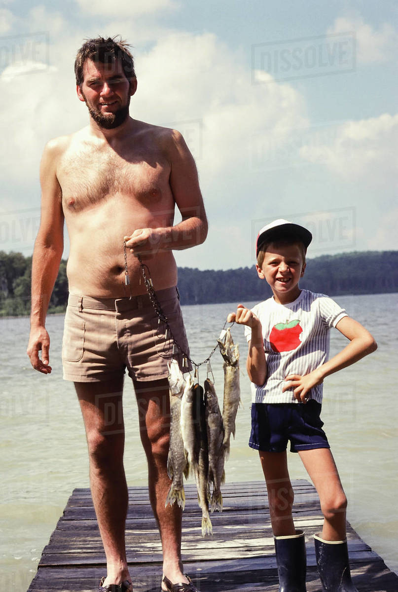 Portrait proud father and son holding line of fresh caught fish ...