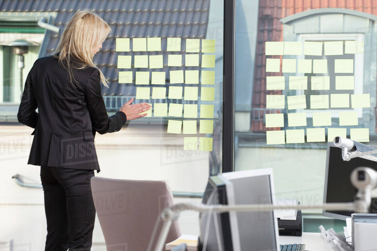 Businesswoman sticking many reminder notes to her office window - Stock ...