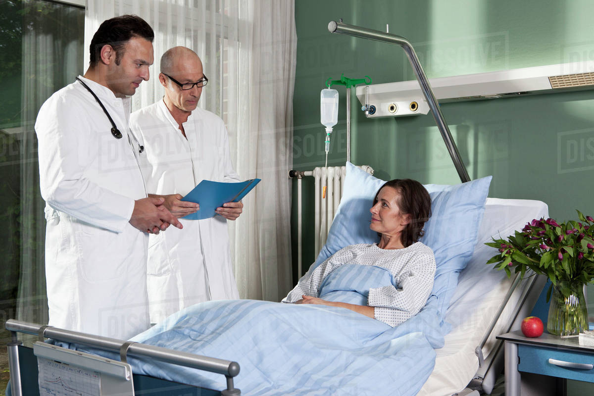 Two doctors next to a female patient in a hospital ward - Royalty-free ...