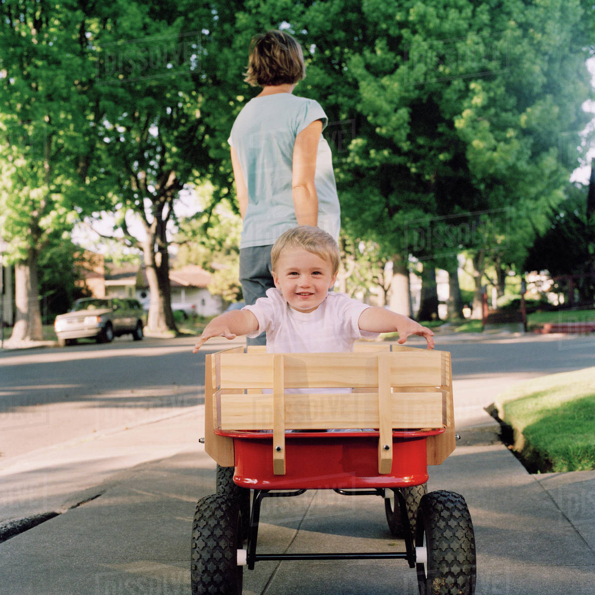 A mother pulling her young son in a wagon, focus on boy - Royalty-free ...